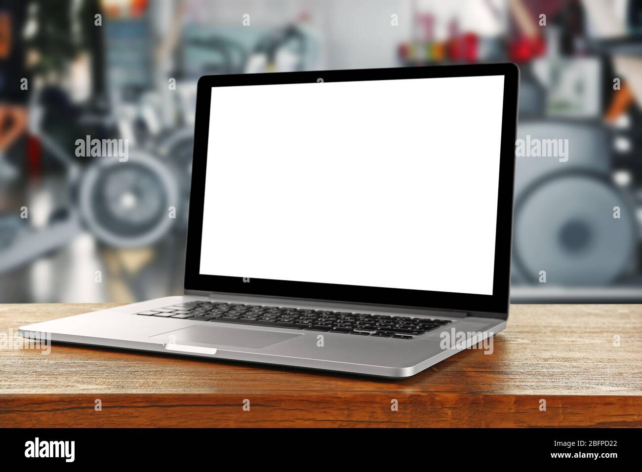 Laptop with blank screen on blurred gym background Stock Photo - Alamy