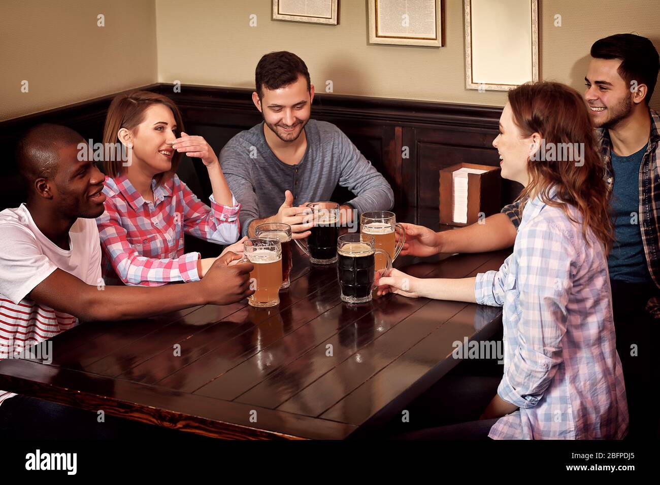 Happy friends drinking beer in pub Stock Photo - Alamy