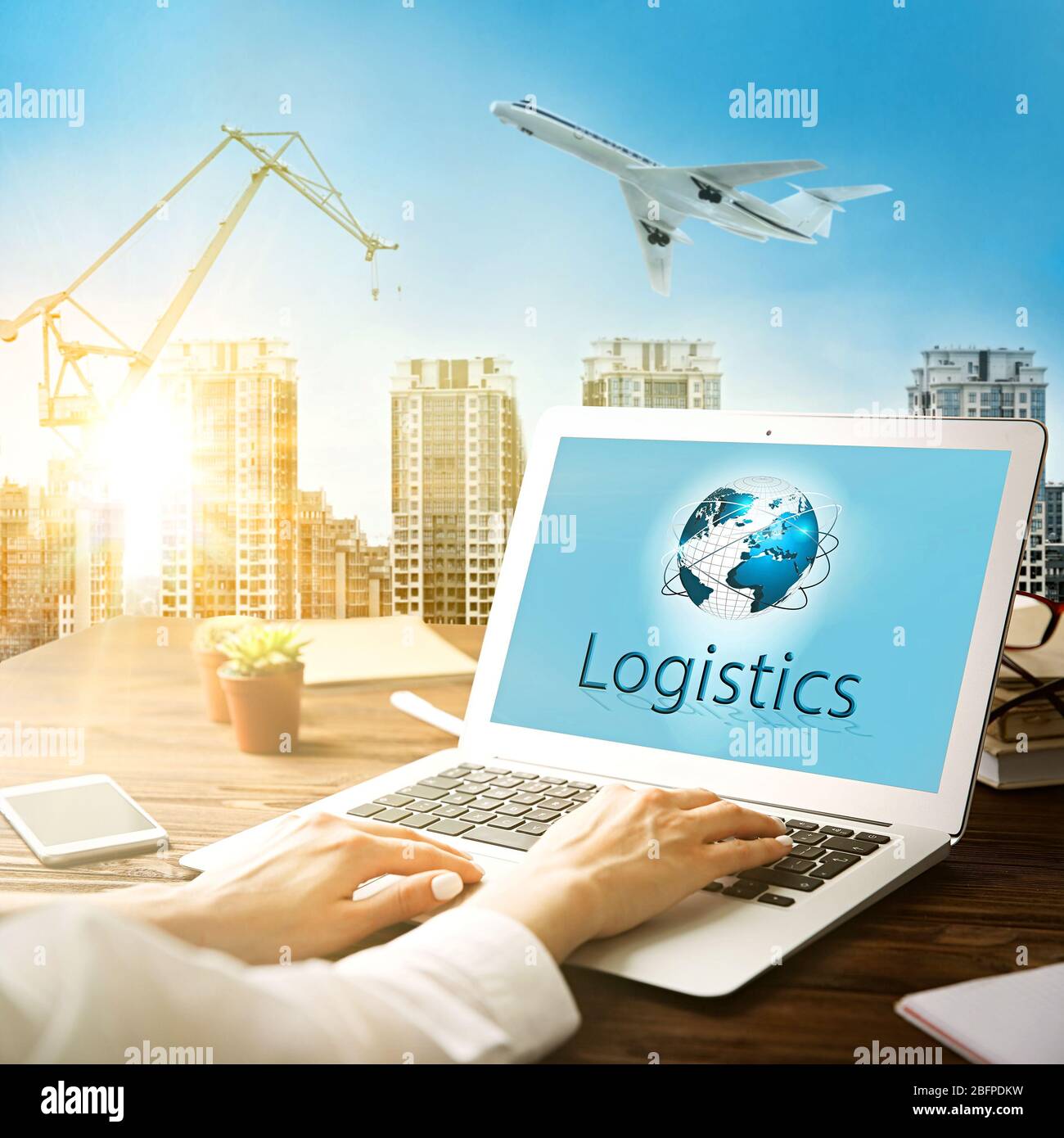 Female hands working with laptop, word LOGISTICS on screen. Cityscape ...