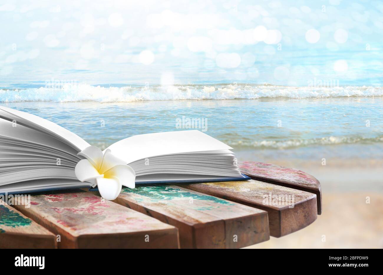 Reading during summer vacation. Book and flower on landscape background ...