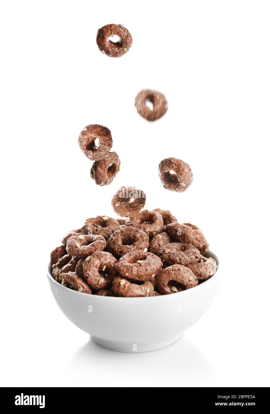Corn rings falling into bowl on white background Stock Photo - Alamy