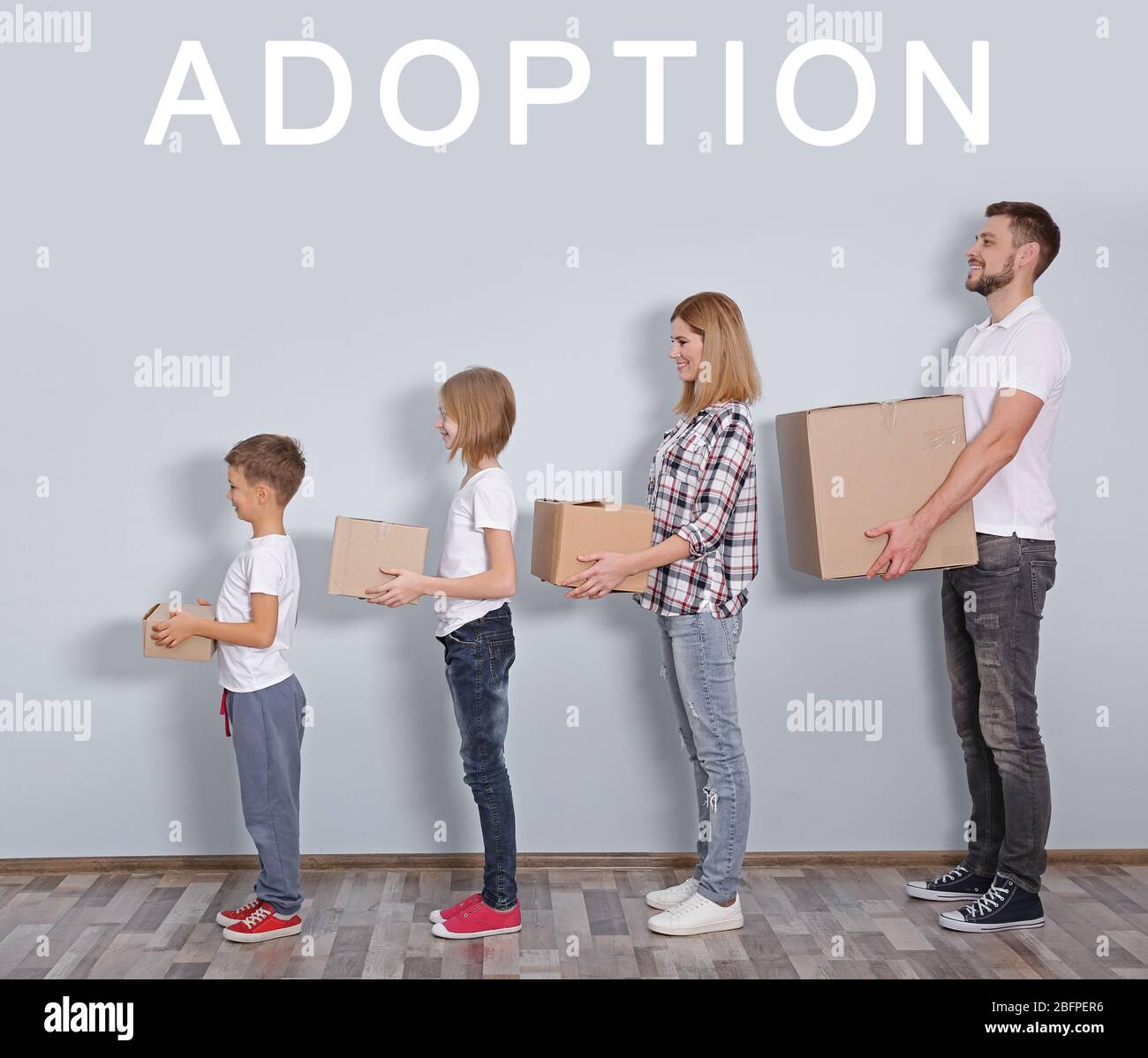 Adoption concept. Happy family with boxes standing against wall ...