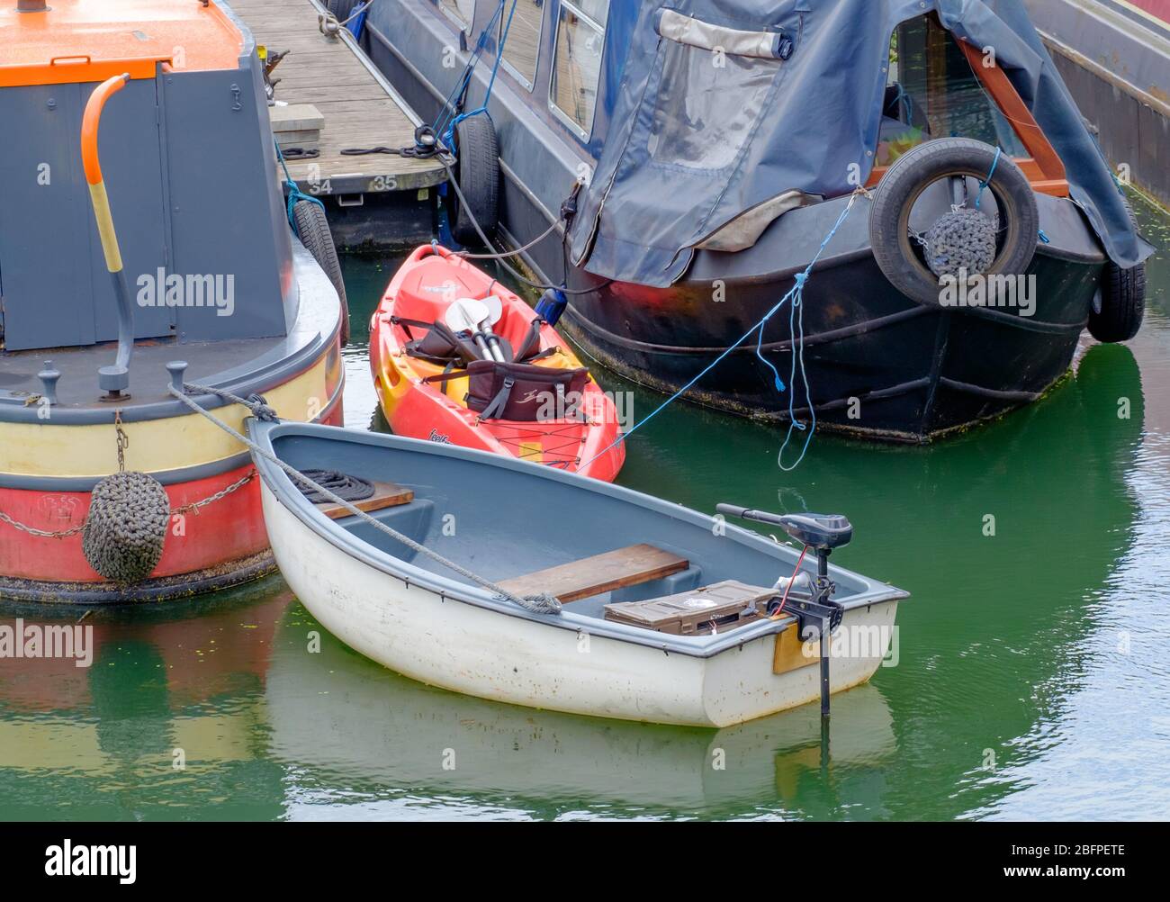 A row boat and canoe tied up next to boats moored at Limehouse Marina ...
