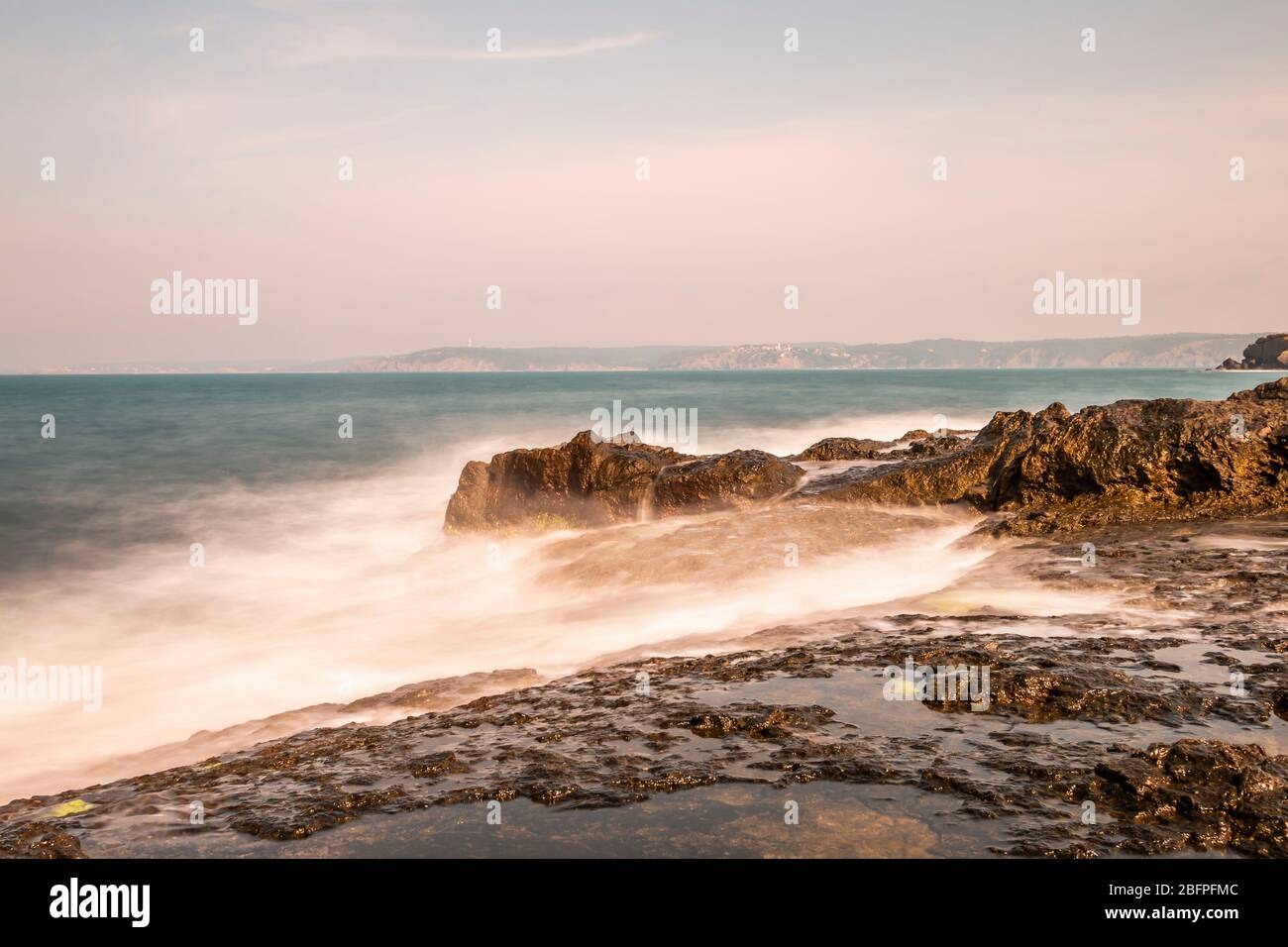 Beautiful rocky beach lit up by first rays of morning sunshine with ...