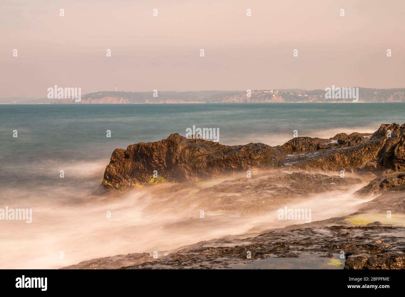 Beautiful rocky beach lit up by first rays of morning sunshine with ...
