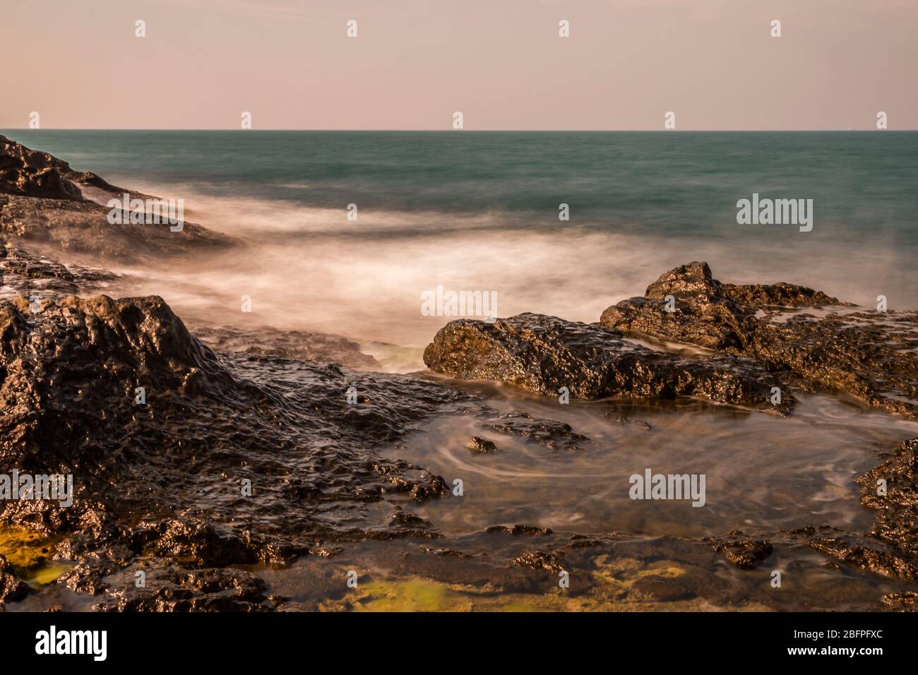 Beautiful rocky beach lit up by first rays of morning sunshine with ...