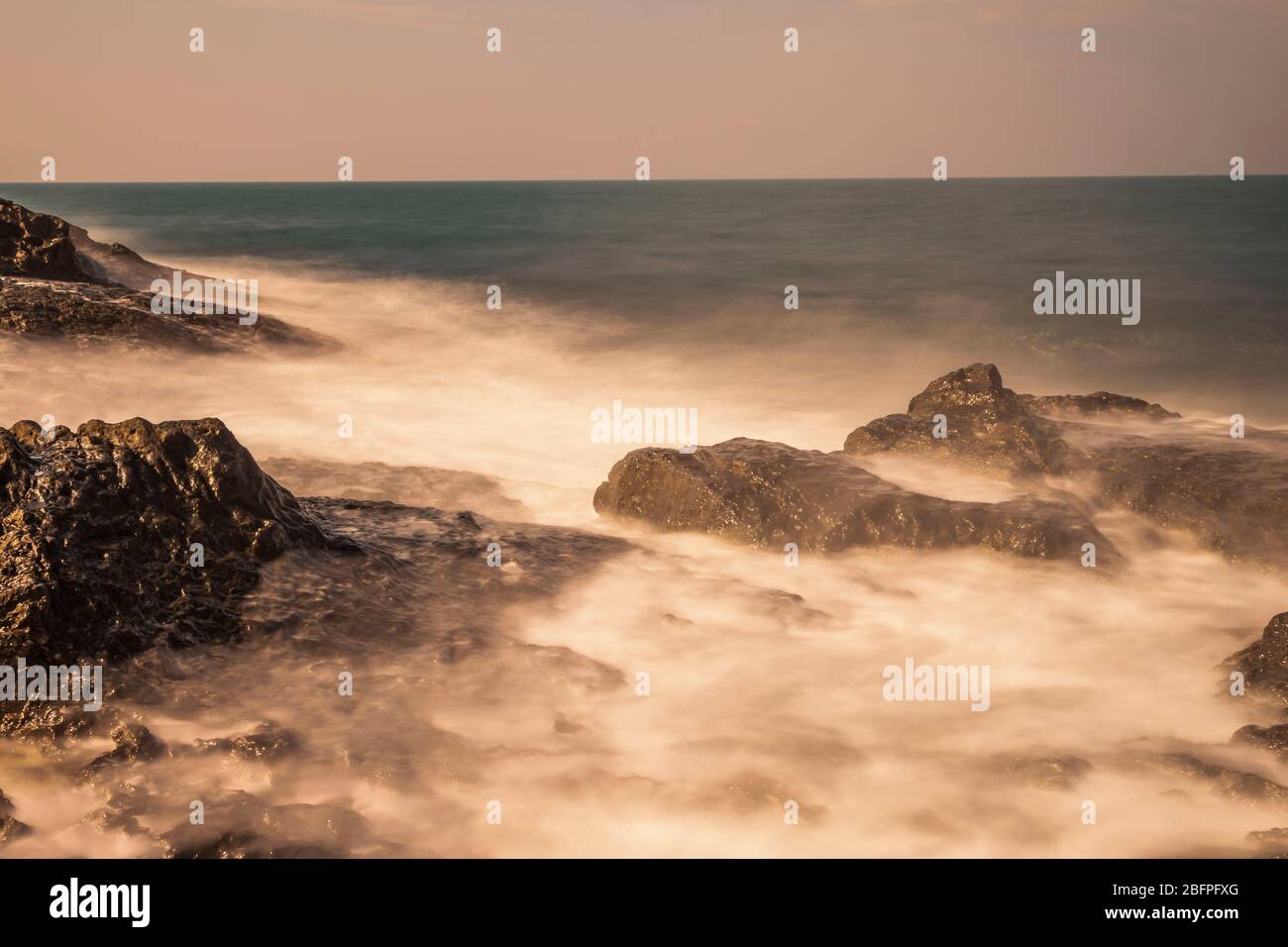 Beautiful rocky beach lit up by first rays of morning sunshine with ...