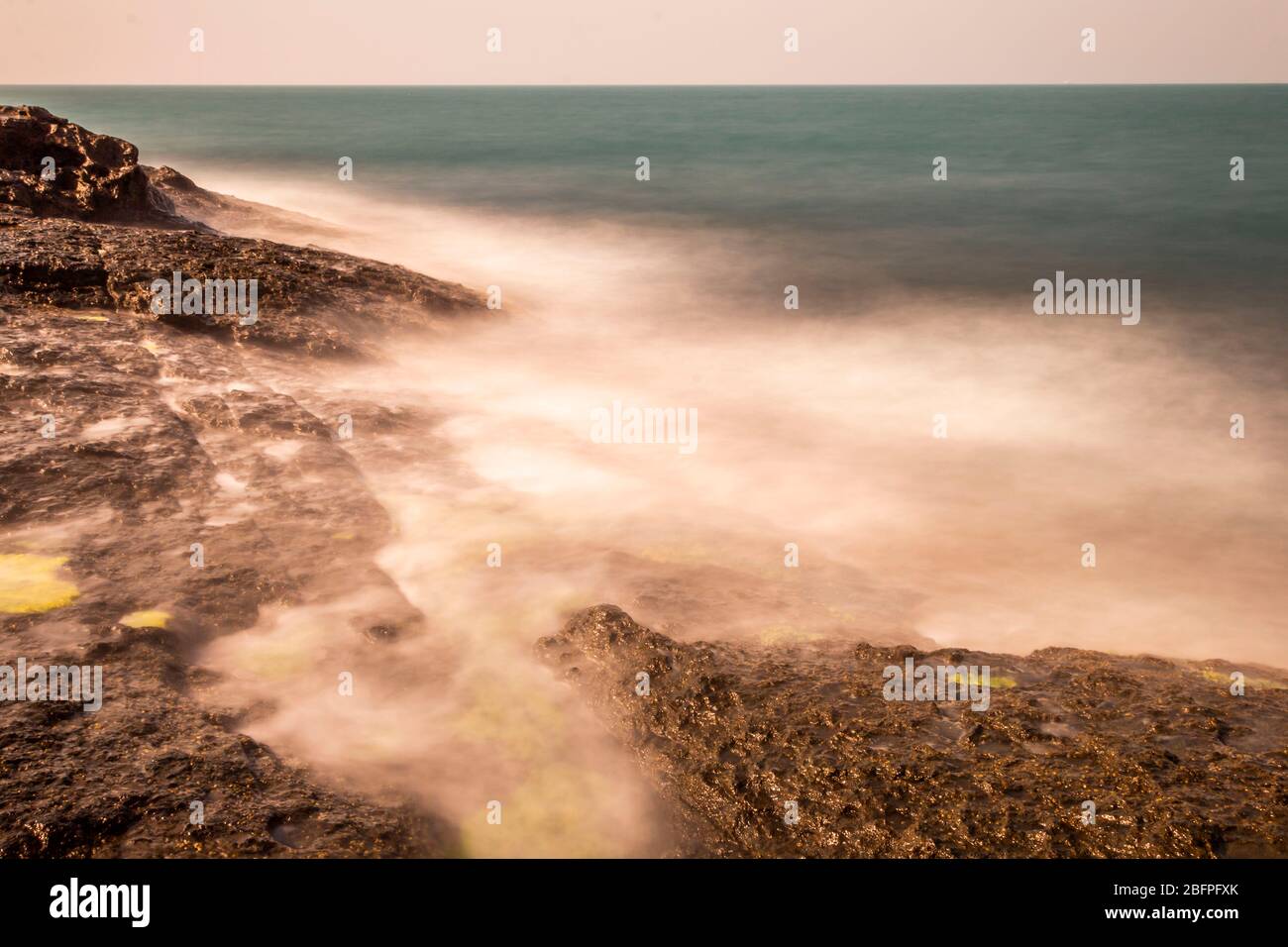 Beautiful rocky beach lit up by first rays of morning sunshine with ...
