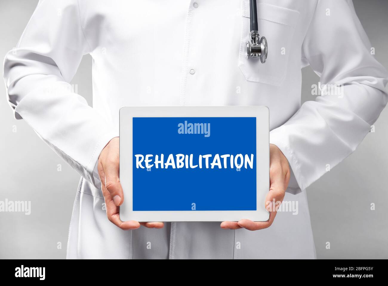 Recovery concept. Doctor holding tablet, closeup. Word REHABILITATION ...