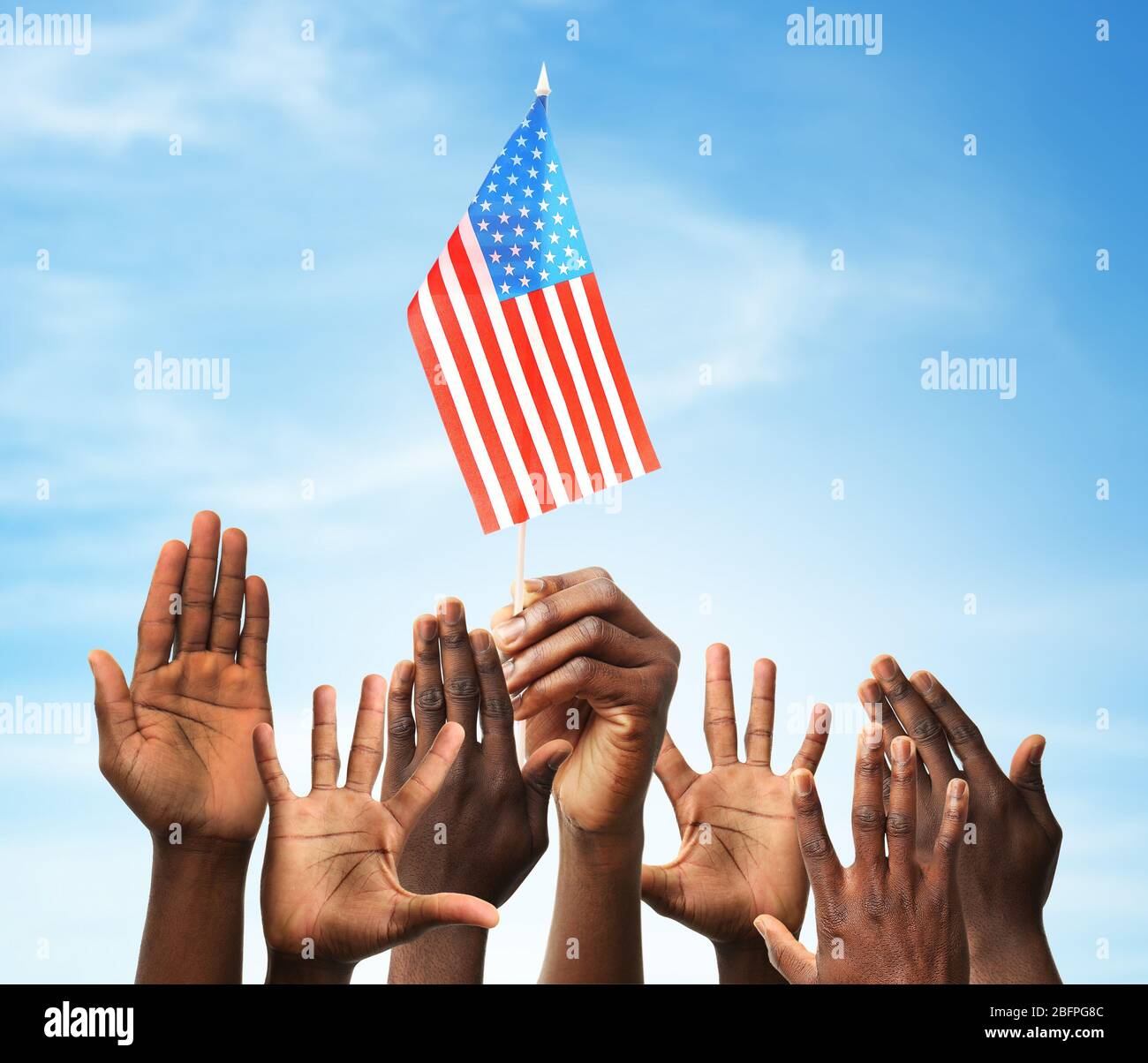 Man waving American flag and other people raising hands on sky ...