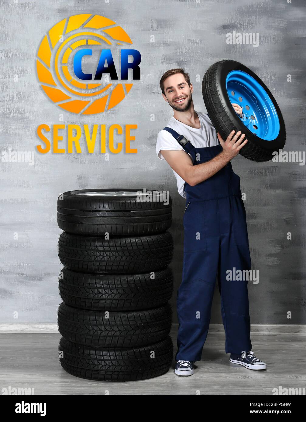 Concept of car service. Mechanic with wheels on color wall background ...