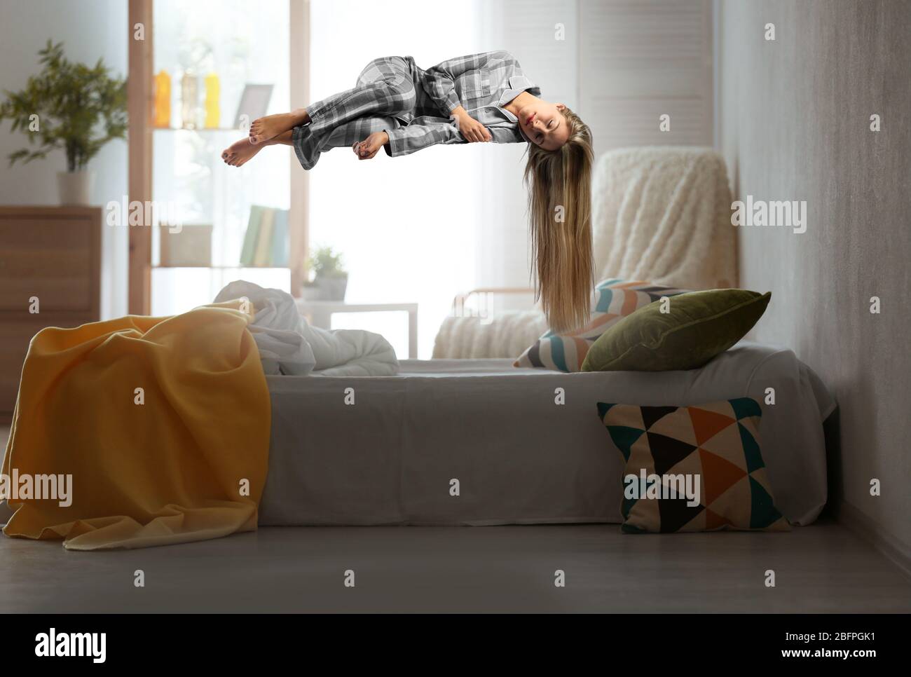 Sleep paralysis concept. Young woman levitating over bed Stock Photo ...