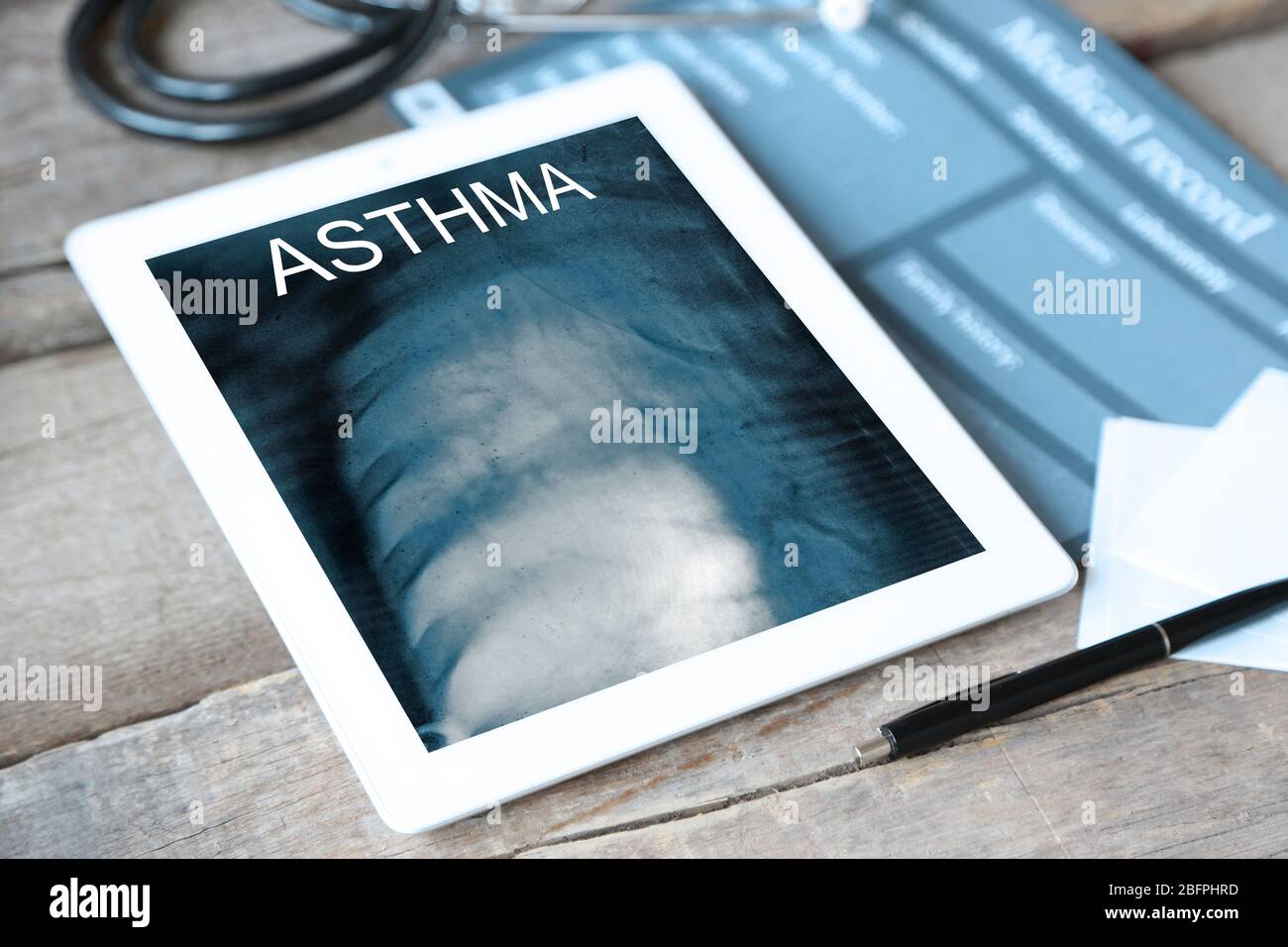 Asthma and health care concept. Tablet with medical record on wooden ...