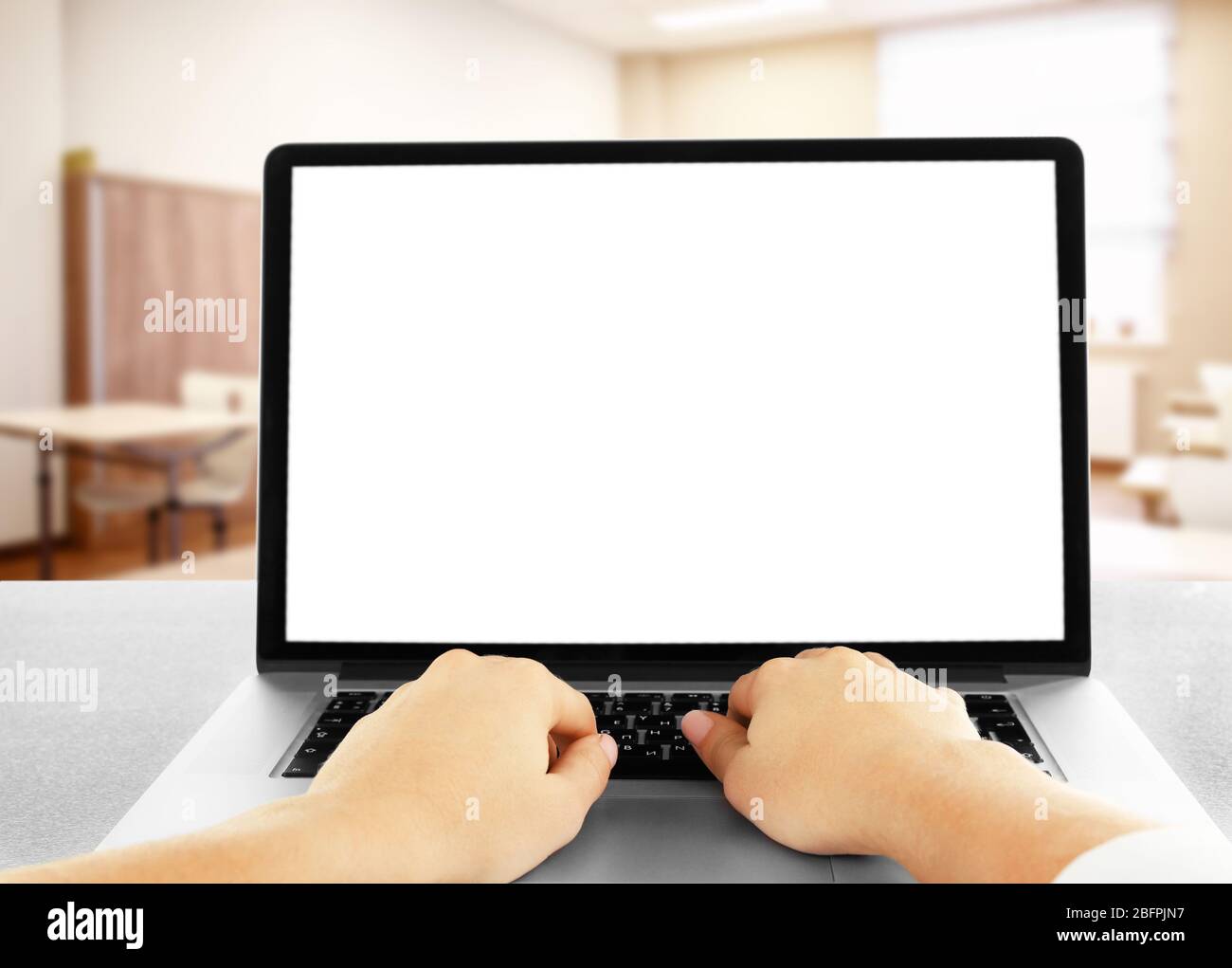 Teacher working with laptop at table in classroom Stock Photo - Alamy