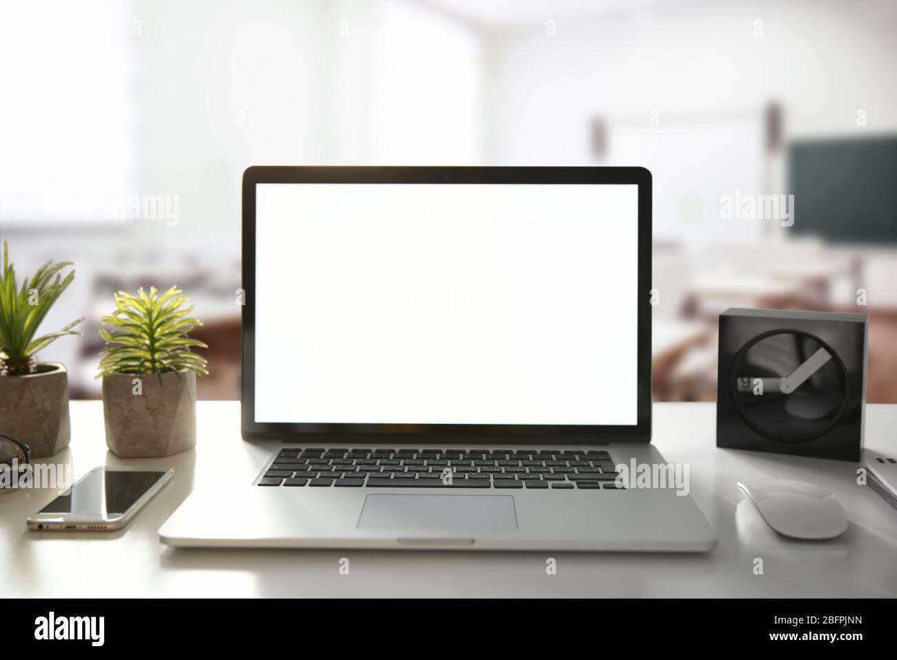 Modern laptop with blank screen on table in classroom Stock Photo - Alamy