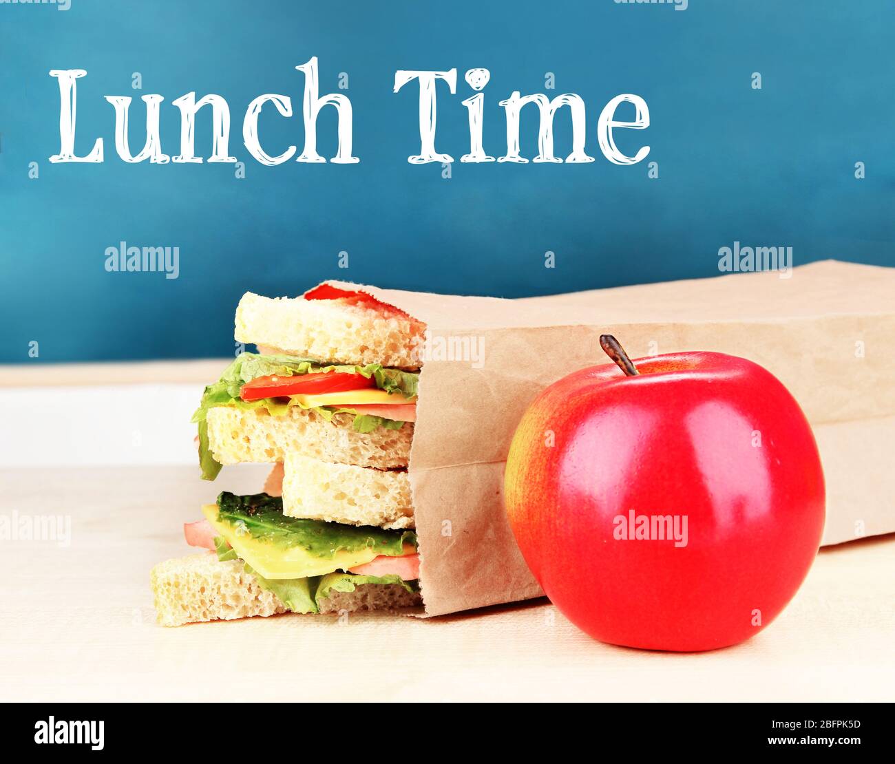 Lunch time concept. Tasty sandwiches in paper bag and apple on wooden ...