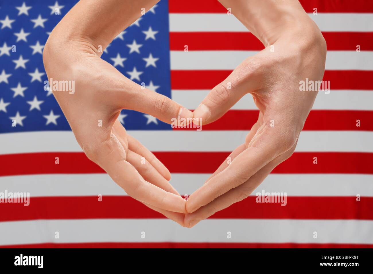 Woman and man making heart of hands and American flag on background ...
