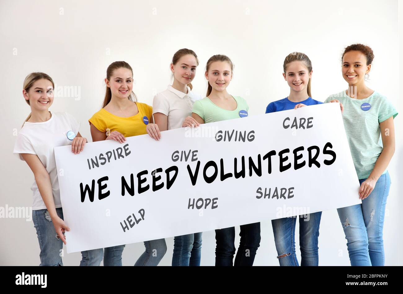 Group of teens holding poster with text WE NEED VOLUNTEERS on color ...