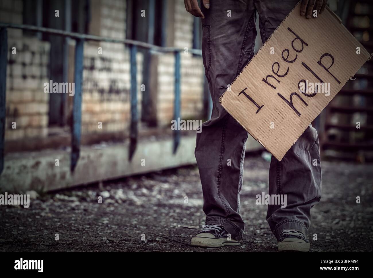 Poverty concept. Poor man holding cardboard sheet with text I NEED HELP ...