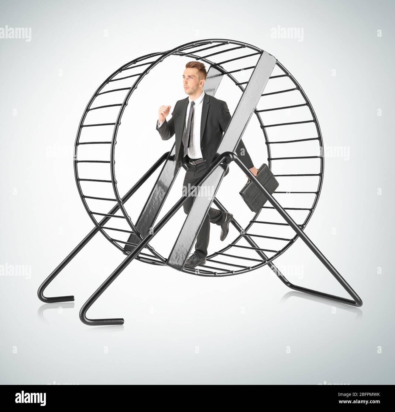 Young man running in wheel on light background. Business rat race ...