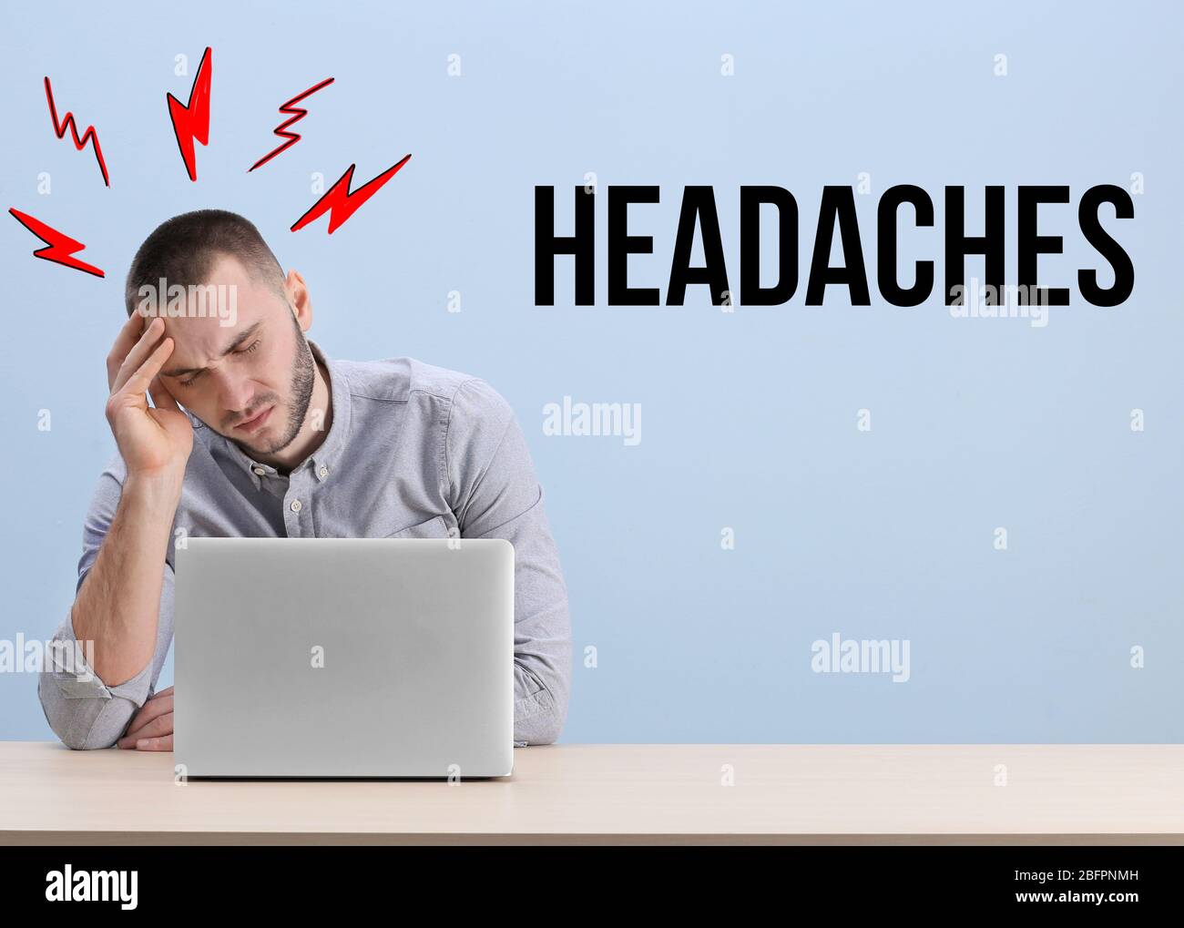 Young man suffering from headache while working with laptop and drawn ...