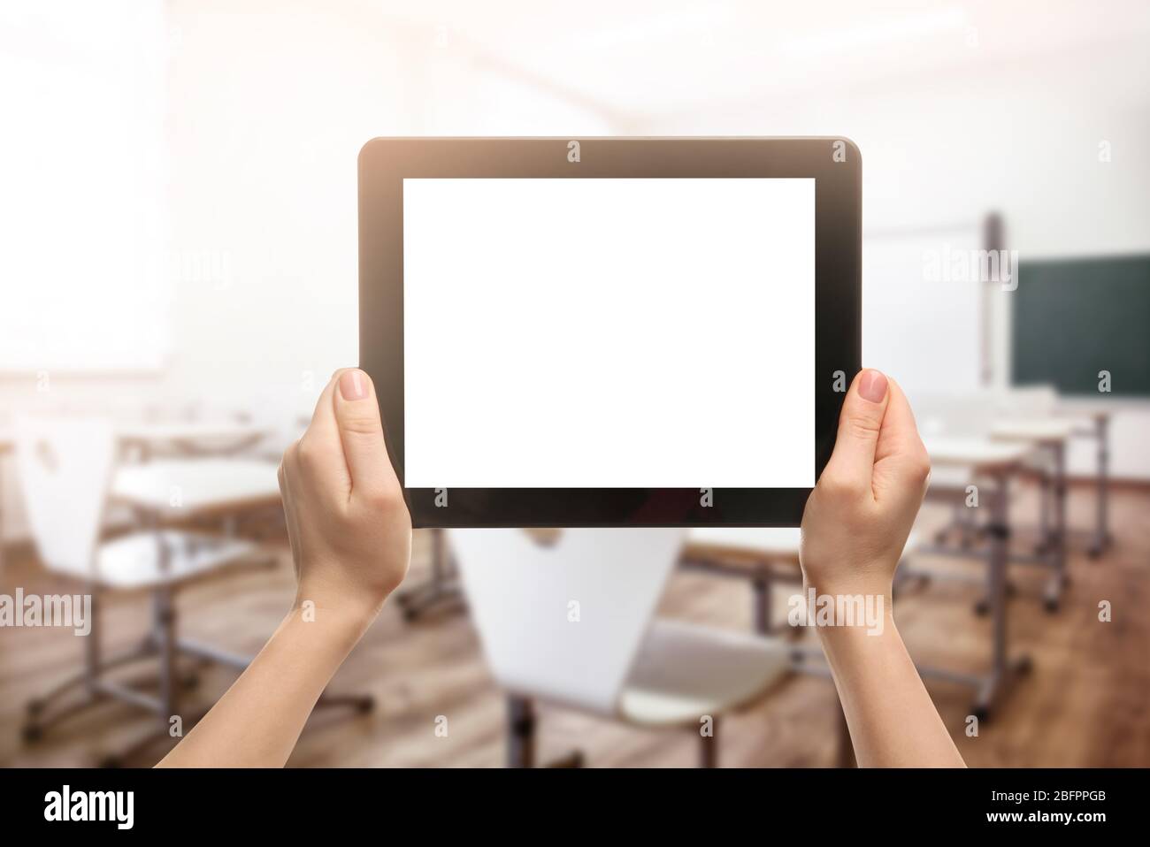 Teacher holding tablet with blank screen and classroom on background ...