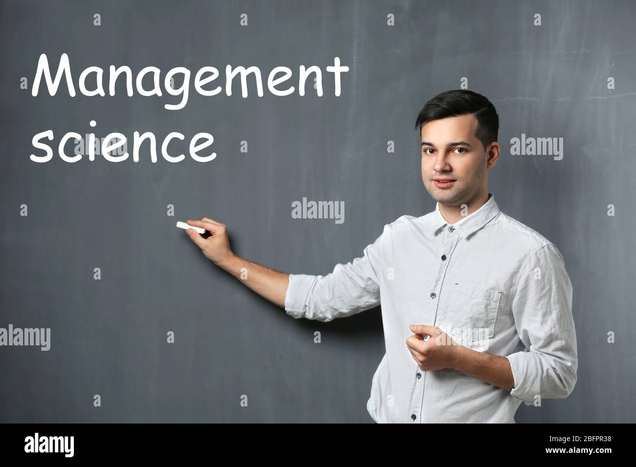Concept of management science. Young man with piece of chalk on gray ...
