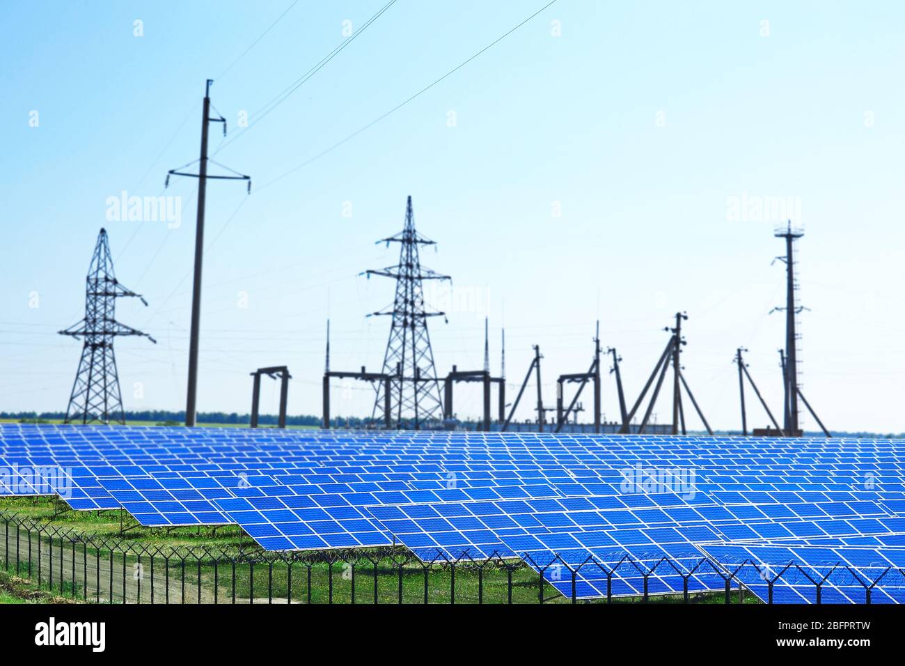 Solar panels and electrical transmission towers in field. Concept of ...