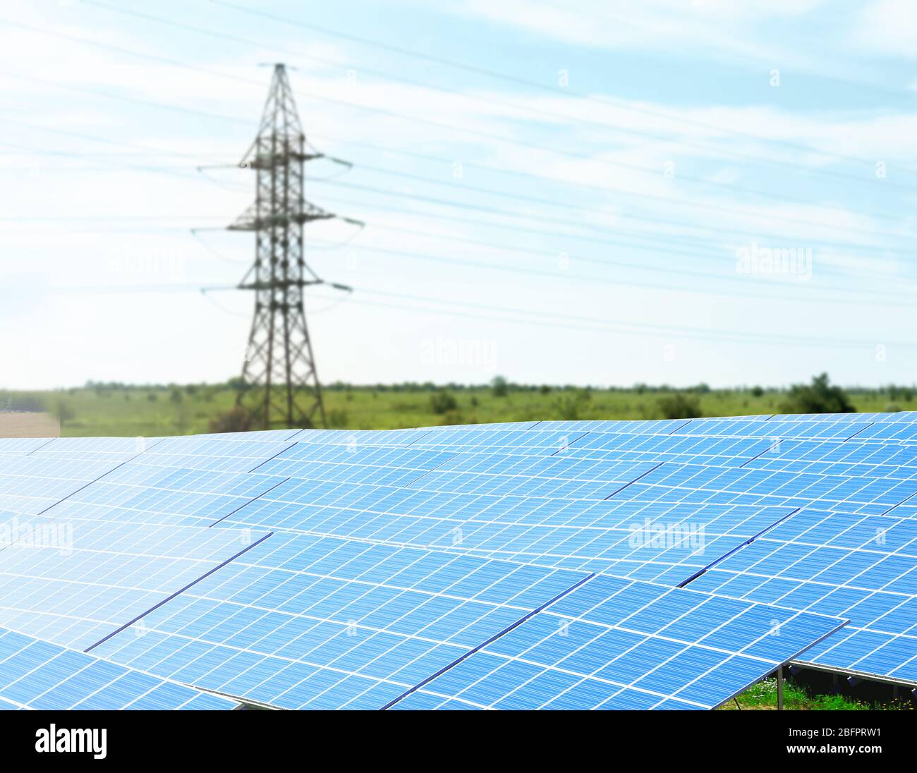 Solar panels and electrical transmission tower in field. Concept of eco ...