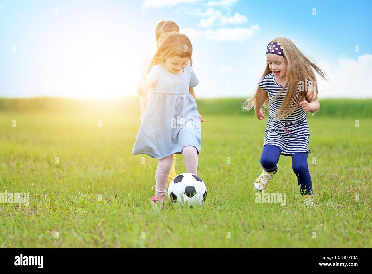 Cute little girls playing football on green grass Stock Photo - Alamy