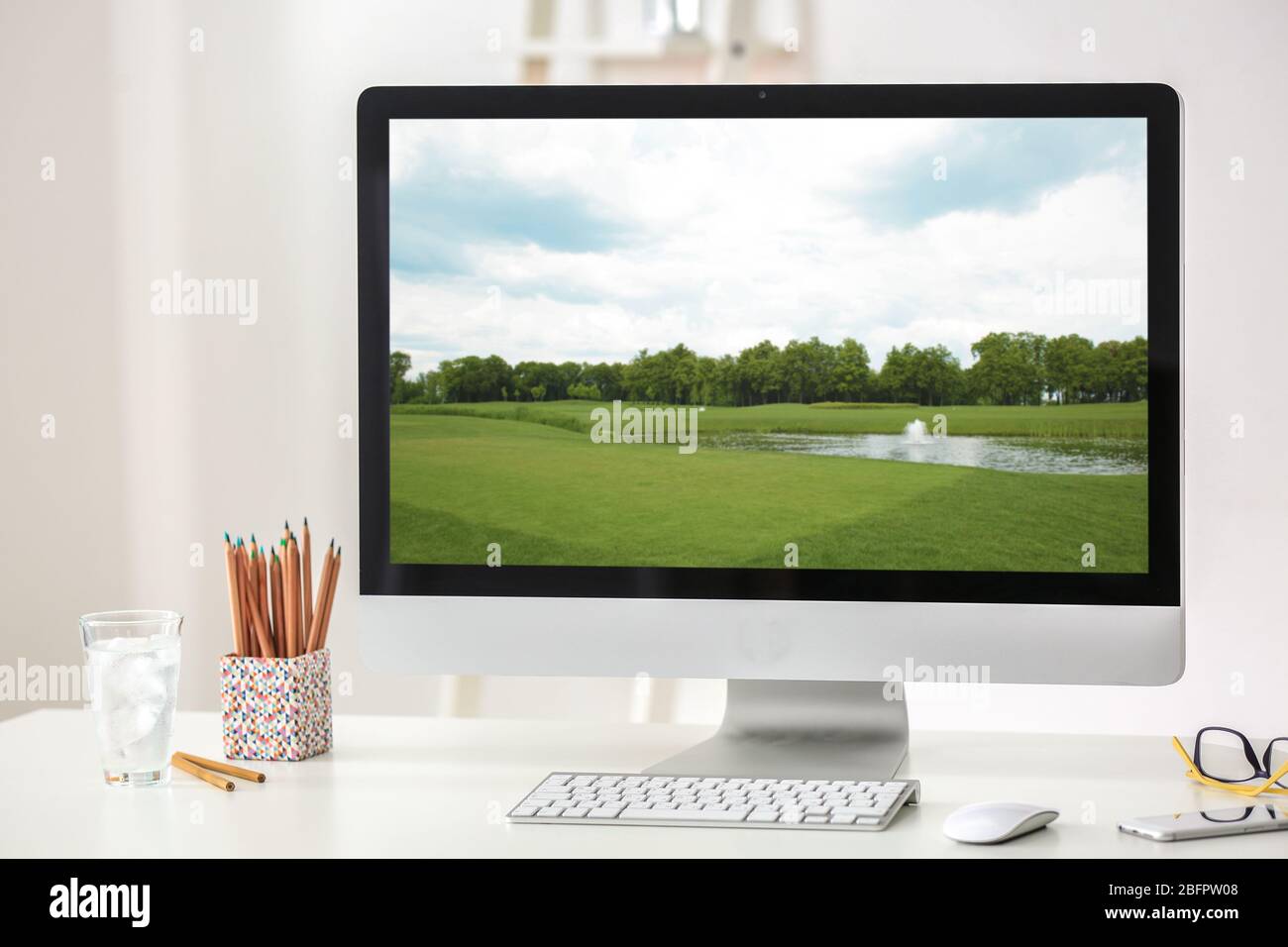 Workplace with computer monitor and wallpaper of landscape on screen ...