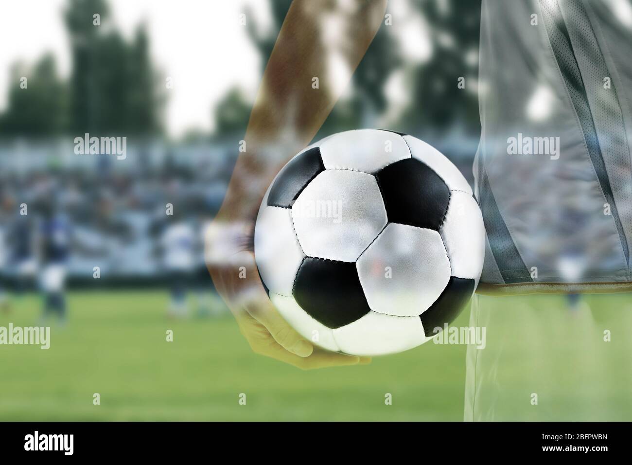 Double exposure of professional football player with ball and stadium ...