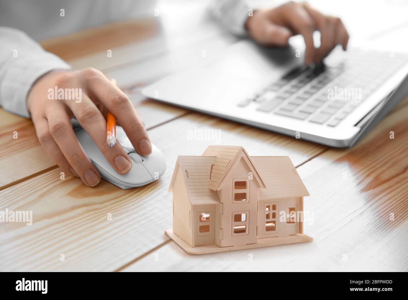 Real estate agent working with laptop and model of house on table in ...
