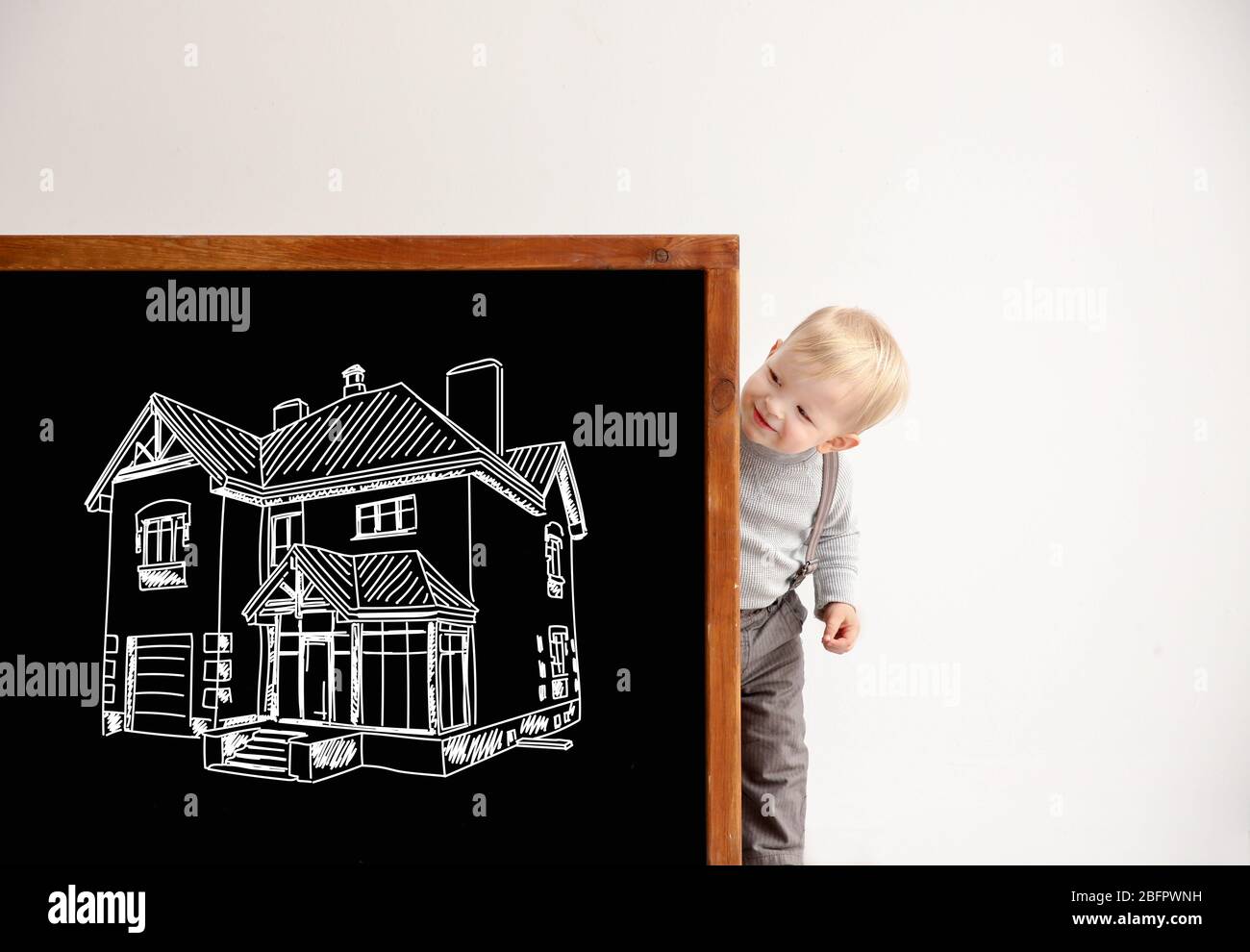 Cute little boy and drawing of house on blackboard Stock Photo - Alamy