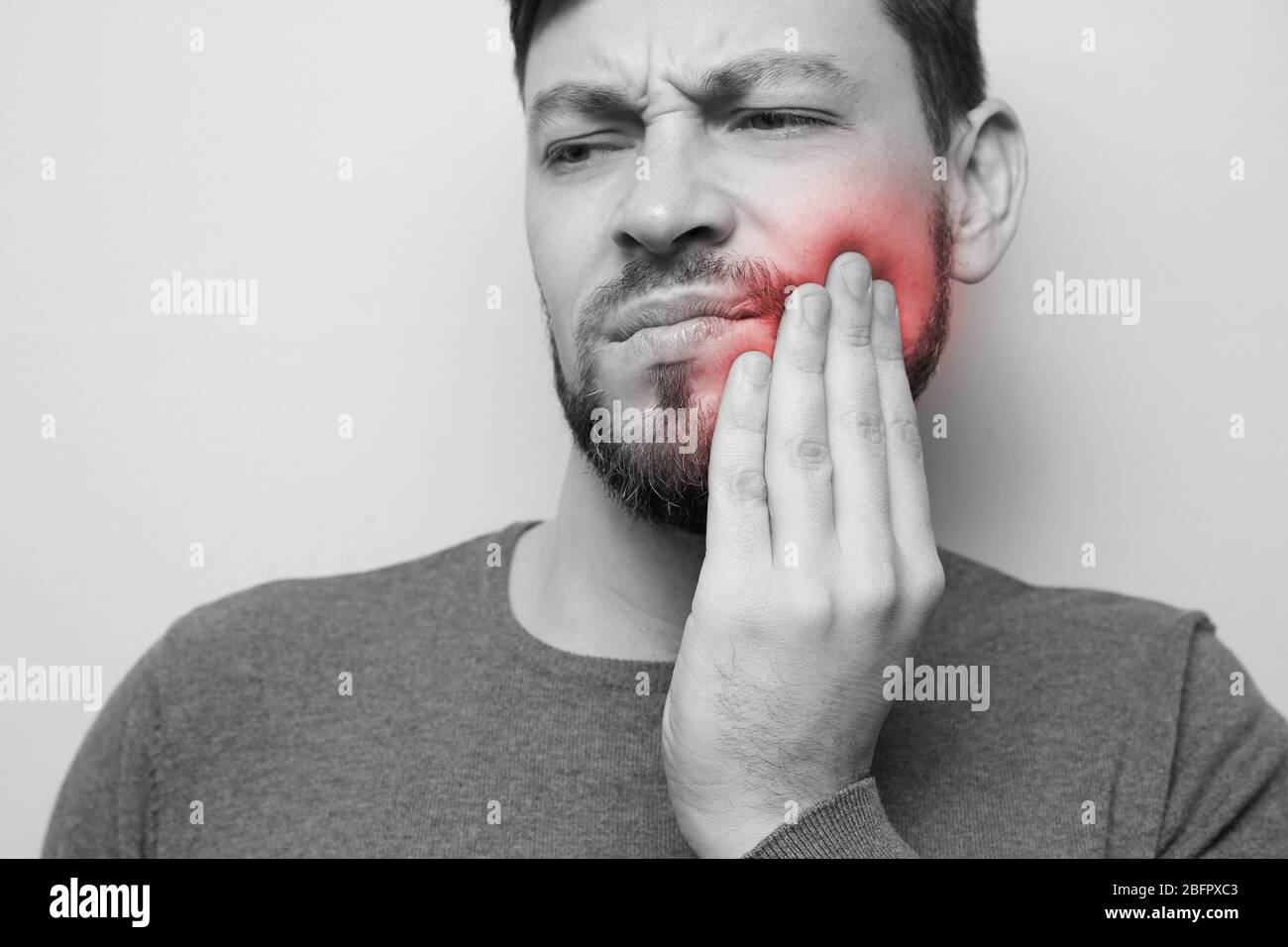 Young man suffering from toothache on grey background Stock Photo - Alamy