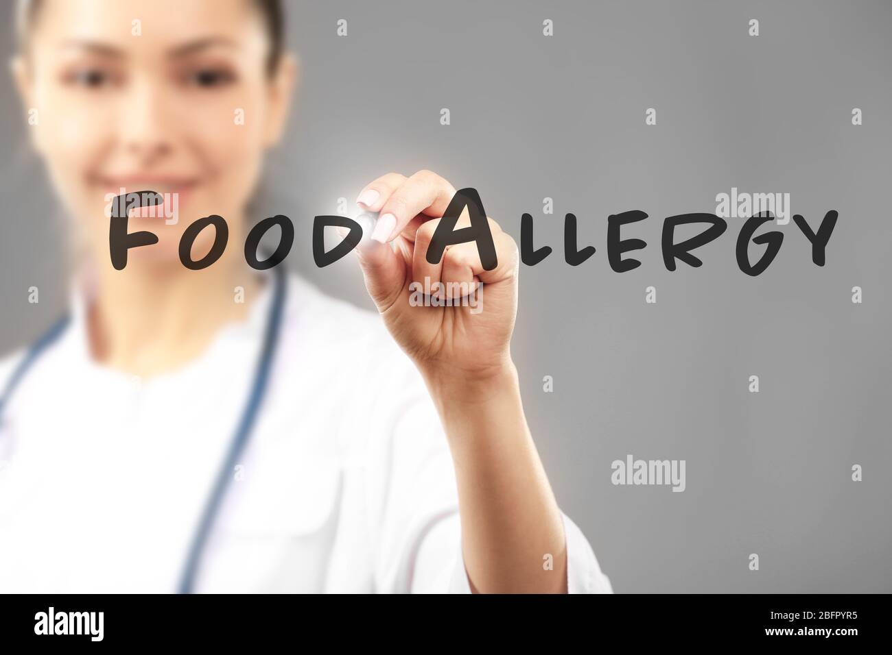 Doctor writing text FOOD ALLERGY on virtual screen against grey ...