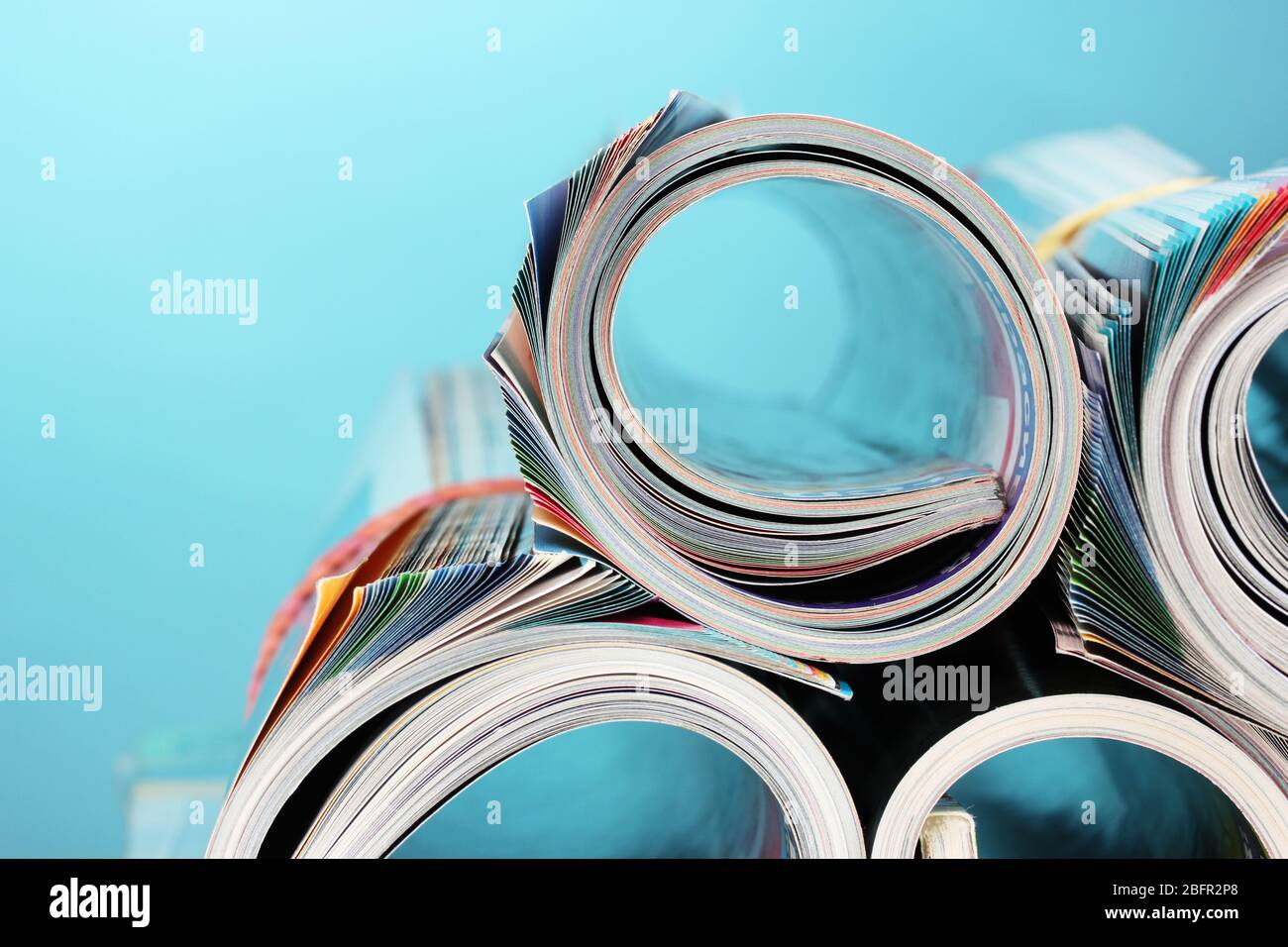 Rolled up magazines on blue background Stock Photo - Alamy