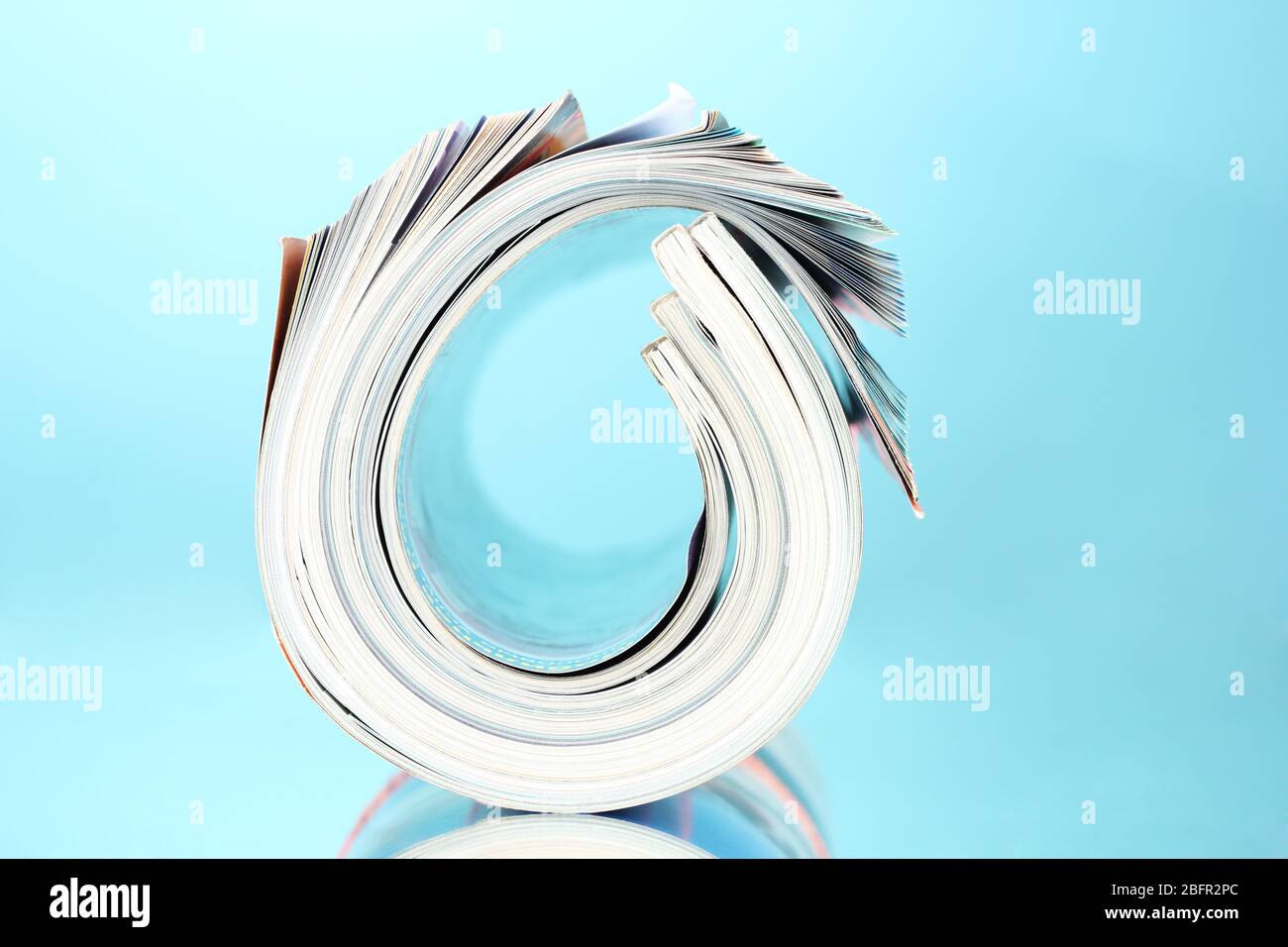 Rolled up magazines on blue background Stock Photo - Alamy