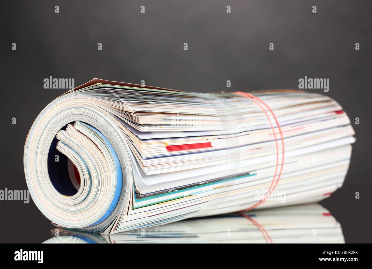 Rolled up magazines on gray background Stock Photo - Alamy