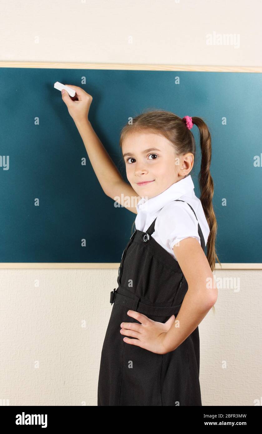 beautiful little girl writing on classroom board Stock Photo - Alamy