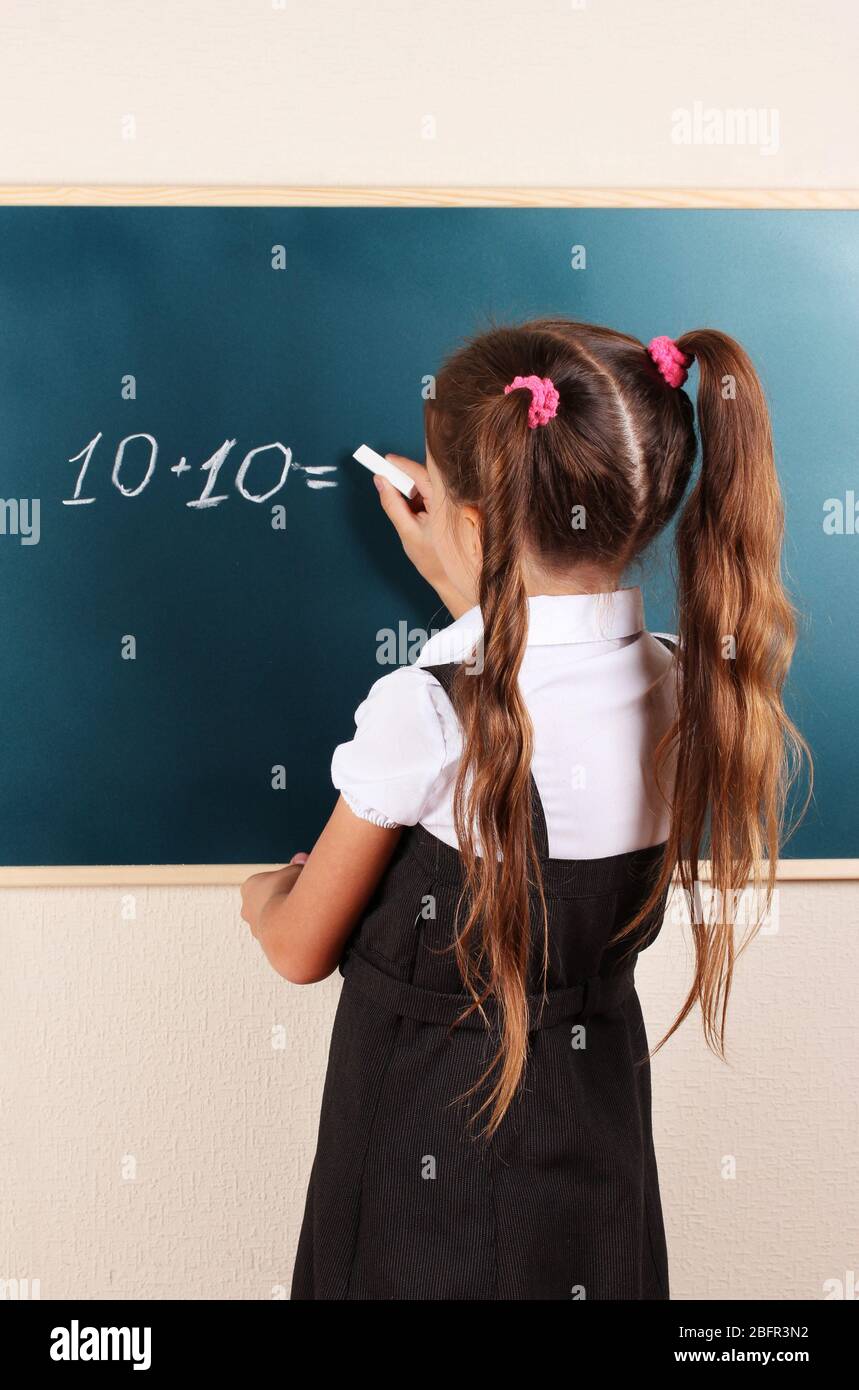 beautiful little girl writing on classroom board Stock Photo - Alamy