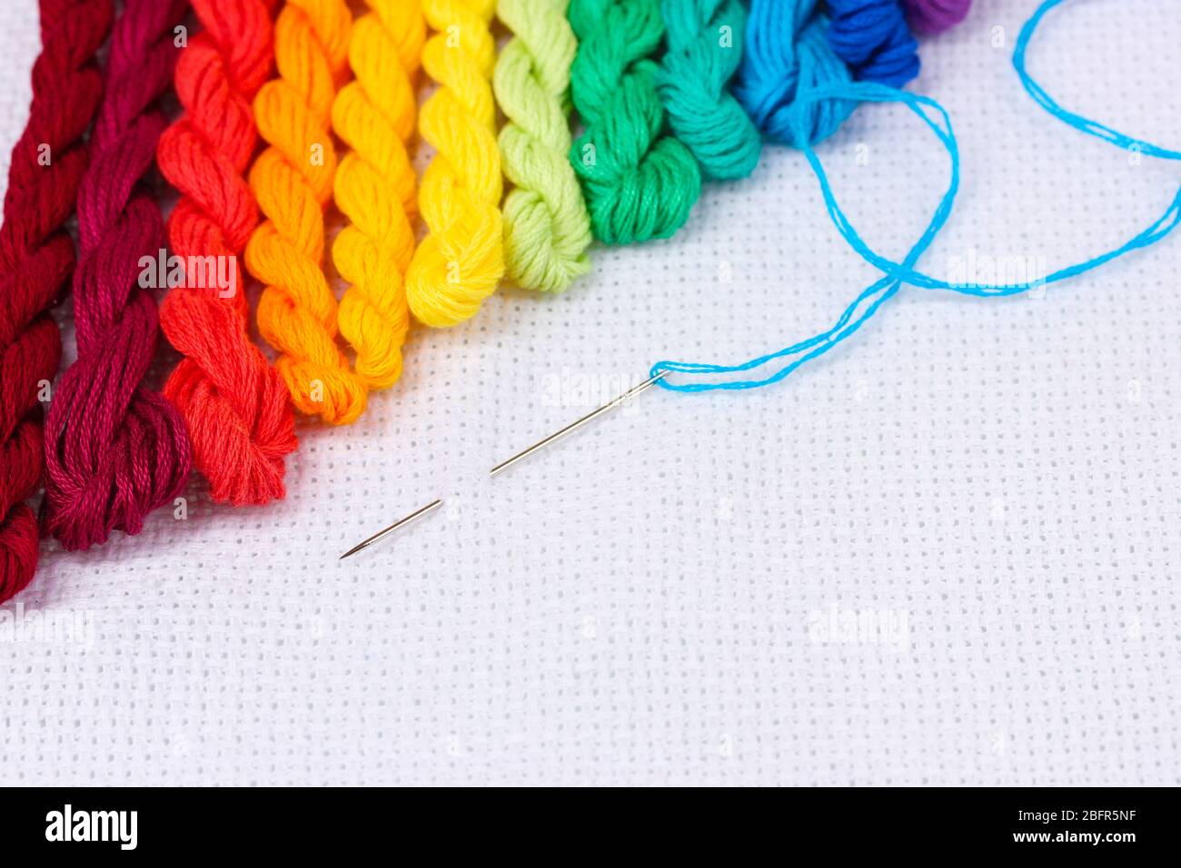 sewing threads for embroidery and needle with a thread on white cotton ...