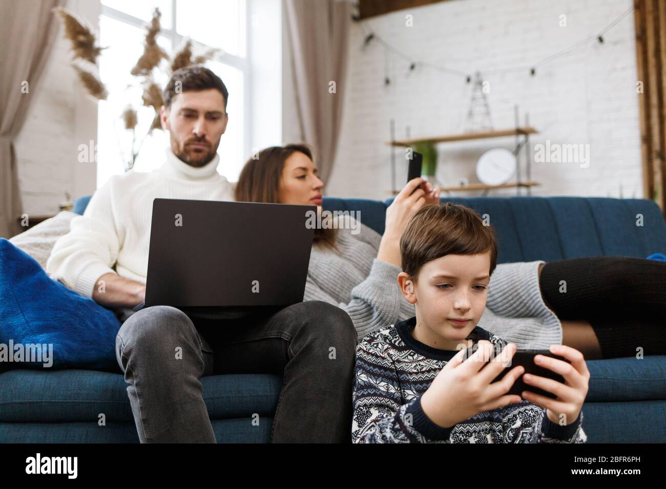Mother, father and son using laptop and mobile phones at home. Family ...