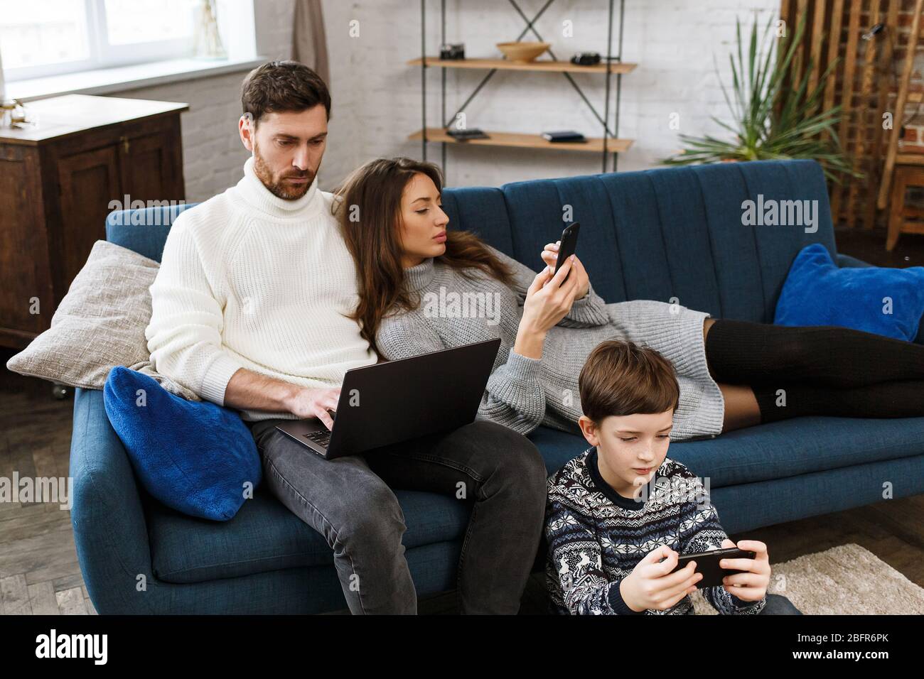 Mother, father and son using laptop and mobile phones at home. Family ...