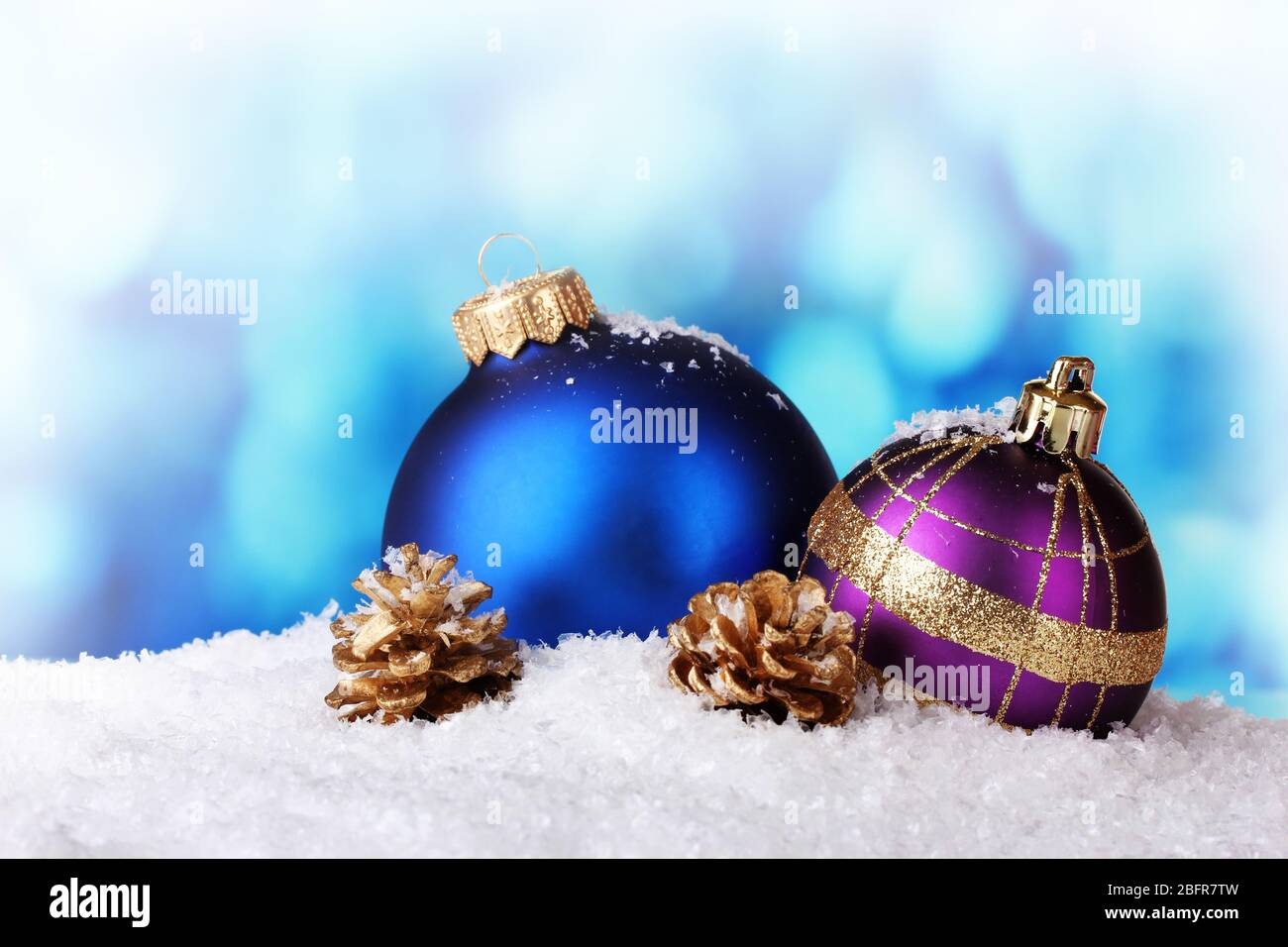 beautiful blue and purple Christmas balls and cones in snow on blue ...