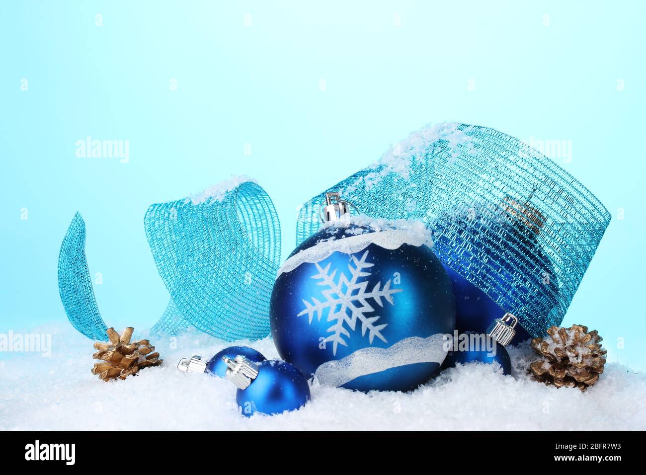 beautiful blue Christmas balls and cones in snow on blue background ...