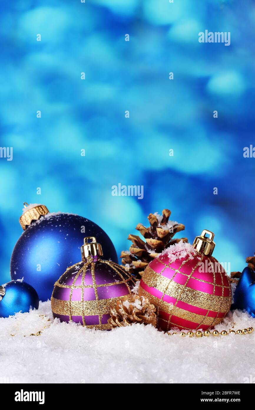 beautiful bright Christmas balls and cones on snow on blue background ...