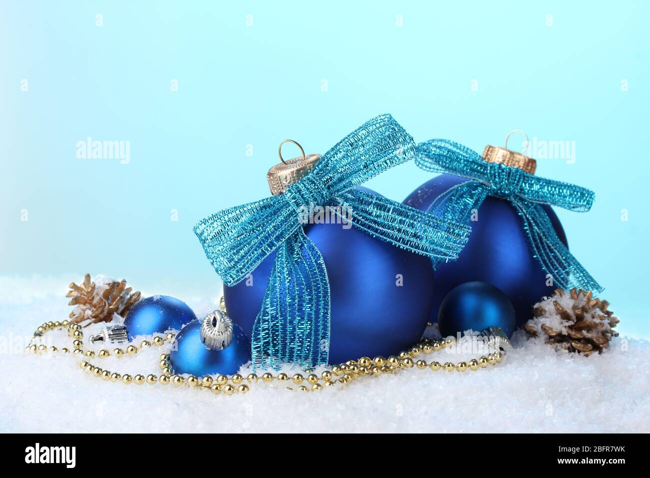 beautiful blue Christmas balls and cones on snow on blue background ...