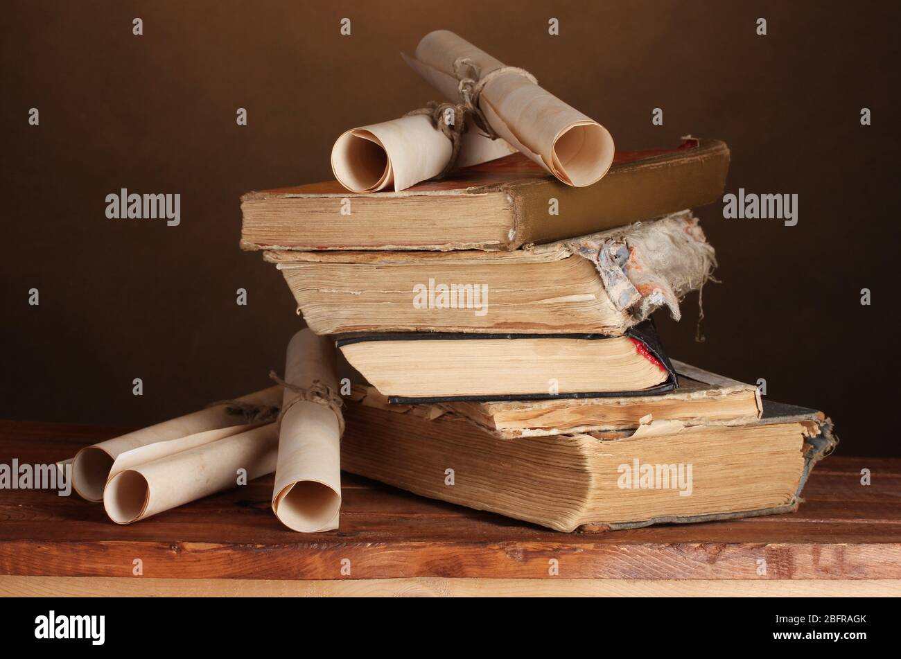Pile of old books and scroll on brown Stock Photo - Alamy