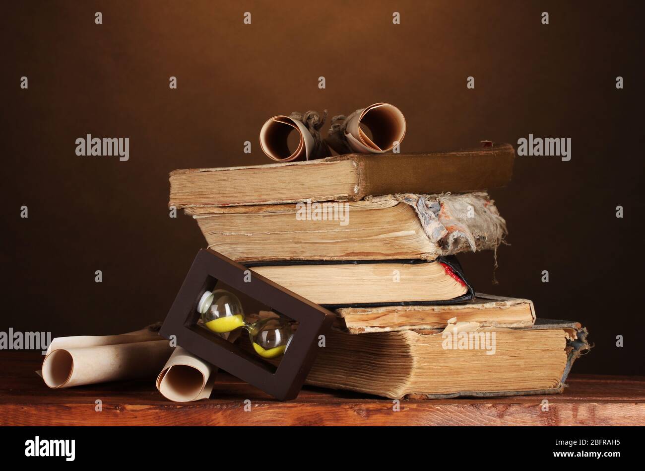 Pile of old books and scroll on brown Stock Photo - Alamy